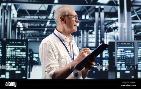 Elderly Engineer Looking Around High Tech Data Center Using Clipboard To Crosscheck Disaster