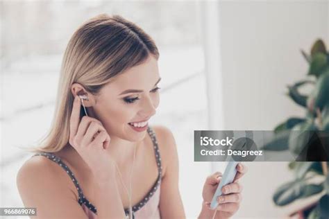 자신감 평화로운 성공 예쁜 매력적인 명랑 세련 된 여자 손에 스마트 폰 데 음악 선택 헤드폰 조화 좋은 하루 이빨 미소 거실 실내 사용 하 여 Mp3 플레이어에 대한 스톡