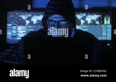 Man Geek Hacker In Hood With Glasses Working At Computer While Blue