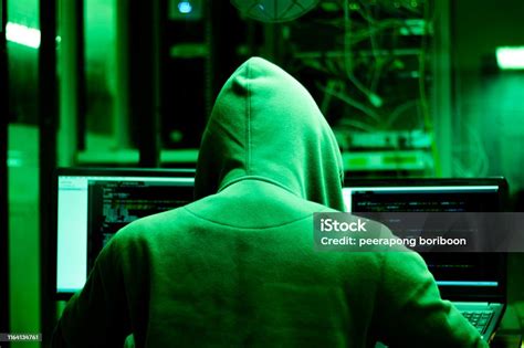 크래커는 회사의 몸값 정보에 바이러스를 만들고 있다 여러 화면이 있는 컴퓨터로 바이러스 프로그램 코드를 작성하는 크래커입니다 녹색 빛 방에서 해커 개념 랜섬웨어에 대한 스톡