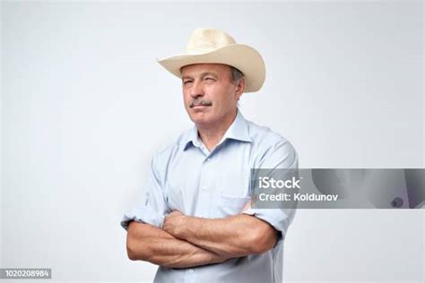 성숙한 남자 그의 카우보이 모자를 조정 하 고 회색 배경에 서 있는 동안 카메라를 보고 결심에 대한 스톡 사진 및 기타 이미지 결심 남성 남자 Istock
