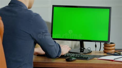 Young Man Working On Desktop Computer With Green Screen Mock Up In