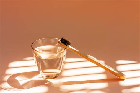 복숭아 색파스텔 배경에 대나무 칫솔과 물 한 잔 자연채광의 그림자 생분해성 페소날 케어 및 플라스틱 무폐기물 개념 0에 대한 스톡 사진 및 기타 이미지 Istock