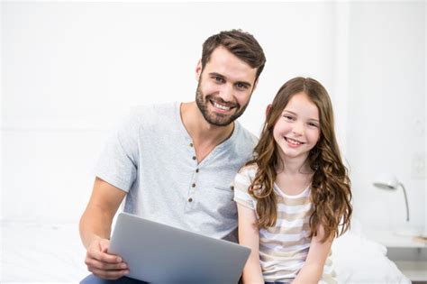 Retrato De Pai E Filha Usando O Laptop Na Cama Foto Premium
