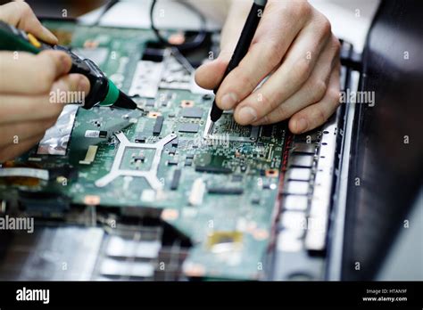 Closeup Shot Of Male Hands Testing Electric Current In Circuit Board Of Disassembled Laptop