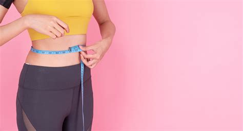 날씬한 몸 아시아 여자는 분홍색 배경에 측정 테이프 허리선을 사용합니다 어린 소녀 측정 허리 둘레 체중 감량 성공 고립 된 파스텔 배경 위에 모양 건강 관리 다이어트 완벽한