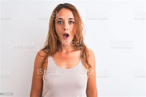 흰색 고립 된 배경에 앉아 캐주얼 티셔츠를 입고 젊은 빨간 머리 여자는 두려워 하고 깜짝 표정 두려움과 흥분 얼굴충격 T 셔츠에 대한 스톡 사진 및 기타 이미지 Istock
