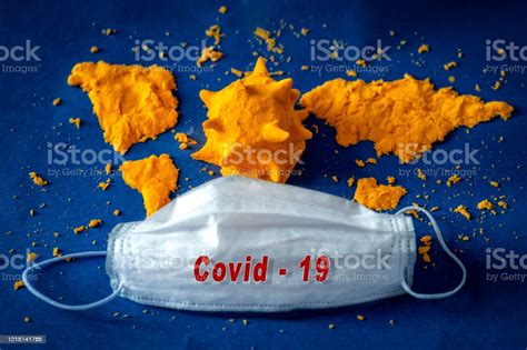 파란색 배경에 오렌지 색의 운동 모래에서 코로나 바이러스와 대륙의 윤곽의 볼륨 이미지 비문 코비드 19와 의료 흰색 마스크