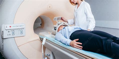 Radiologic blonde model technician help at mature female patient lying on a CT Scan bed Stock 写真