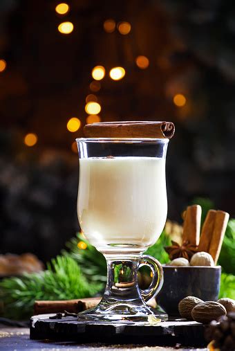 새해 또는 크리스마스 에그노그 칵테일 우유 계란 어두운 럼주와 함께 뜨거운 겨울 또는 가을 음료 나무 배경에 유리에 계피와 육두구를 뿌려 축제 장식 0명에 대한 스톡 사진