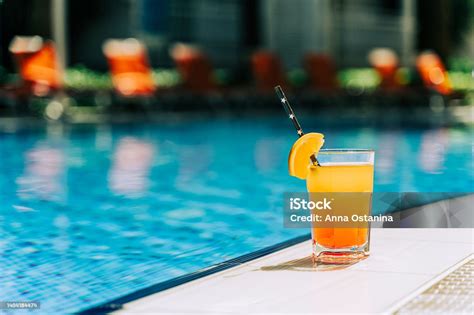 수영장 옆의 열대 반짝이는 칵테일 수영장 근처에 서있는 오렌지 레모네이드 과일 칵테일과 함께 유리 샷 호텔 수영장에서 여름 알코올 무료 음료 안녕하세요 여름 휴가 휴가 0