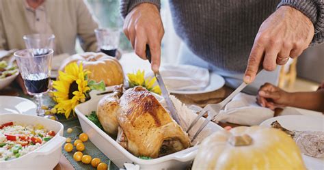 저녁 식사 또는 축하 행사에서 로스트를 자르는 남자의 손으로 닭고기 음식 및 가족 집에서 추수 감사절이나 크리스마스에 칠면조를