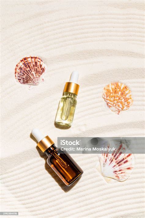 베이지색 바다 모래 자루에 얼굴 피부 관리를 위한 모이스처라이저가 든 스포이드가 있는 두 개의 화장품 병 건성 피부를 위한 제품입니다 위쪽 세로 뷰입니다 건강관리와 의술에