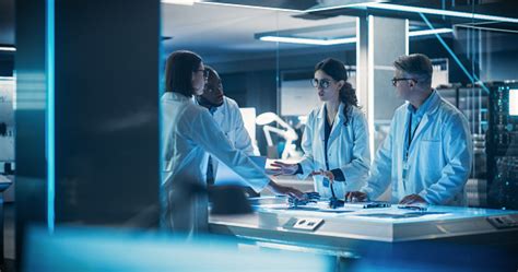 다양한 산업용 로봇 전문가 팀이 바이오닉 로봇의 개발 부품이 있는 테이블 주위에 모였습니다 노트북 컴퓨터를 사용하여 인공 손 프로토타입을 테스트하는 과학자 실험실에 대한