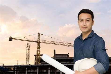 Asian Civil Engineer Holding A Blueprint With Safety Helmet On Head On White Background
