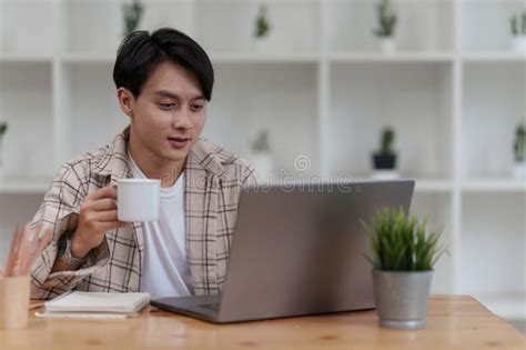 Asian Man Using Laptop Computer Working At Office Creative And New