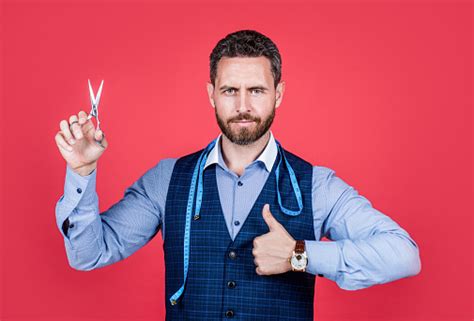 품질과 우수한 양재 전문 재단사가 엄지손가락을 치켜세우는 양재 가위를 들고 있습니다 재봉사 가게 서비스를 만들고 수선하십시오