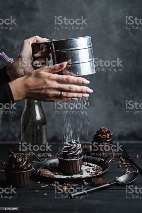 검은 테이블에 초콜릿 모양의 크림이 있는 머핀이나 컵케이크 몇 개 한 여성의 손이 케이크에 가루 설탕을 부스러두는 다 0명에 대한 스톡 사진 및 기타 이미지 Istock
