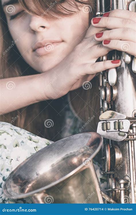 De Zomerportret Van Een Jonge Vrouw Met Saxofoon In Hand Op Een Achtergrond Van Groen Gras Stock