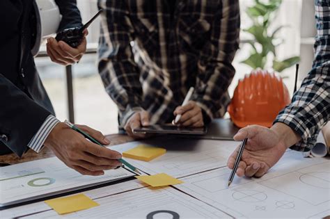 엔지니어는 청사진 위에 건물을 가리키고 노트북을 사용하여 사무실에서 건물 설계 프로젝트를 그립니다 건축 프로젝트를 위한 엔지니어 회의의 이미지 엔지니어 개념 파트너와 협력