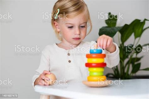 심각한 금발 유아 아이 어린이 흰색 회색 배경에 에코 나무 색 장난감 피라미드와 함께 실내에서 놀고 있는 두 살 소녀 공간을 복사합니다 조기 유치원 개발유치원 게임 12