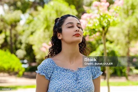 푸른 꽃 여름 드레스를 입은 젊은 백인 여성이 도시 공원에 서서 야외에서 신선한 공기를 마시 며 숨을 쉬고 있습니다 건강한 라이프 스타일의 개념 개념에 대한 스톡 사진 및