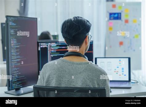 Asian Software Developers Working On Multiple Screens Displaying Code And Application Diagrams