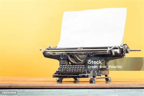 1930 년대 경의 복고풍 타자기 와 종이 빈 위에 나무 책상 정면 노란 벽 배경 빈티지 올드 스타일 필터링 사진 시 문학에