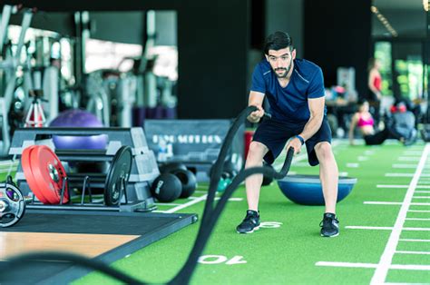 녹색 바닥에 체육관에서 전투 밧줄과 운동 스포티 한 백인 남자 강한 남성 체력과 건물 근육 질의 몸에 대 한 그녀의 실내 운동으로 결정 선수 전투 로프 운동 개념 건강관리와