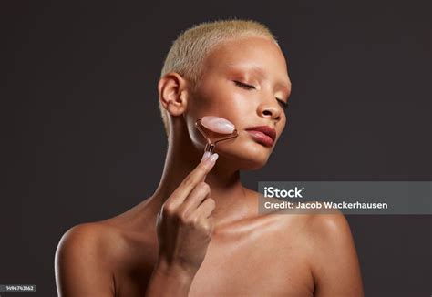 회색 스튜디오 배경에 대한 얼굴 미용 치료를 위한 아름다움의 여성 스킨케어 및 롤러 완벽한 피부를 위한 노화 방지 피부과 또는 미용을 위한 롤링 도구가 있는 아름다운 여성