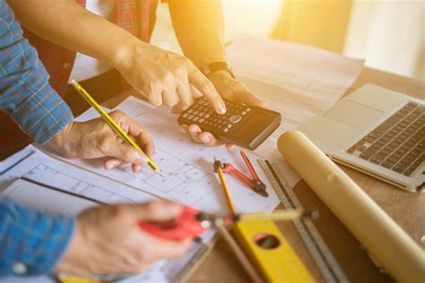 노트북 및 청사진 로프트 오피스의 계산기로 건축 계획 건축 설계 주택 또는 주택 도시 계획 건설 프로젝트를 스케치하기위한 엔지니어링 도구와 함께 일하는 건축가 개념에 대한