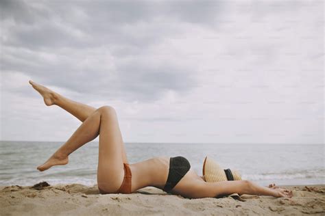 해변에 누워 모자를 쓴 소녀 밀짚모자로 덮고 있는 세련된 젊은 여성 바다 근처 모래 해변에서 휴식을 취합니다 여름 방학 및 여행 마음 챙김과 평온 사진