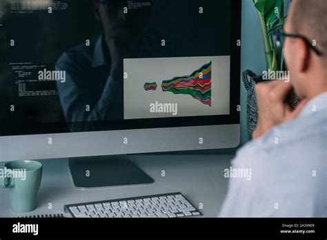 Developer Working Behind The Desk Analysing Diagram On The Monitor