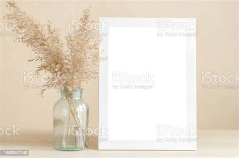 빈 흰색 프레임이 꽃병에 말린 허브가있는 테이블 위에 서 있습니다 클로즈업 포스터 프레임 모형은 중립적인 색상 미니멀한 인테리어입니다 0명에 대한 스톡 사진 및 기타 이미지