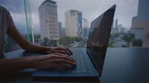 a female programmer works on a laptop overlooking a rainy city stock