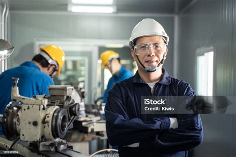 밀링 머신에서 일하는 아시아 기계 노동자 안전 예방 조치를 위해 기계를 작동 할 때 보호 안경과 헬멧을 착용한 기술자 카메라를 바라보는 남자의 초상화 공장 산업 건물에 대한