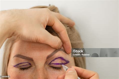 의료 진료소에서 얼굴의 눈 영역을 수정하기 위한 성형 수술 수술 전에 얼굴에 Blepharoplasty 마크업 클로즈업 플라스틱 화장품 작업을 수행하는 의사 안검 성형술에