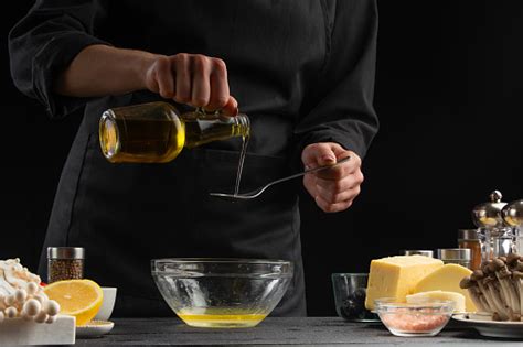셰프는 소스를 만들기 위해 올리브 오일을 붓거나 맛있고 신선한 샐러드를 만들기 위해 드레싱을 합니다 채식과 신선한 음식 미식과 요리 조리법 책과 조리법 검은색 배경에서