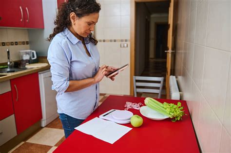 빨간 카운터에 태블릿과 건강 재료를 가진 부엌에 있는 여자 40 44세에 대한 스톡 사진 및 기타 이미지 40 44세 Brand Name Smart Phone 가정