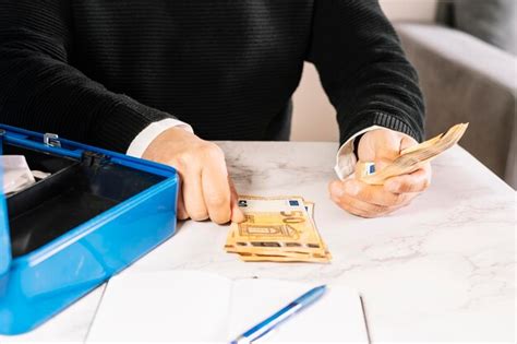 Premium Photo Man Counting Money Next To A Metal Security Box Next To A Pen And Notebook To Premium Photo Man Counting Money Next To A Metal Security Box Next To A Pen And Notebook To