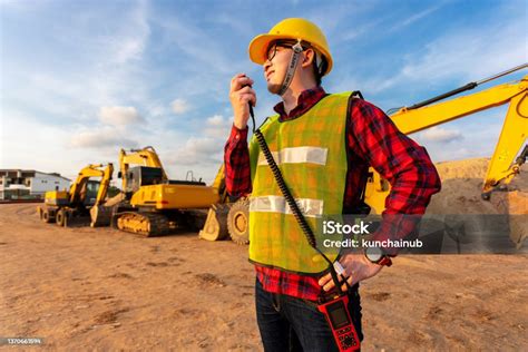아시아 기술자 토목 엔지니어가 무전기로 팀과 이야기하고 엔지니어링 현장 배경에 굴삭기와 운송 건설 공사 프로젝트에 대한 검사 지점에서 포인트 개발에 대한 스톡 사진 및 기타