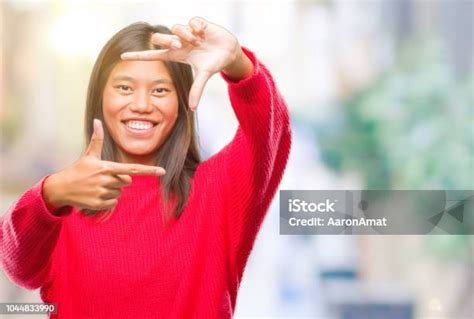 젊은 아시아 여자는 웃 고 손으로 만드는 프레임와 행복 한 얼굴로 손가락 격리 된 배경 위에 겨울 스웨터를 입고 창의력과 사진 개념입니다 가을에 대한 스톡 사진 및 기타