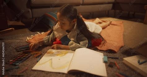 저녁에 거실 바닥에 엎드려 그림을 색칠하는 소녀의 영상 시네마틱 줌인 돌리 Stock Video Adobe Stock