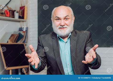 Bearded Professor At School Lesson At Desks In Classroom Teacher And