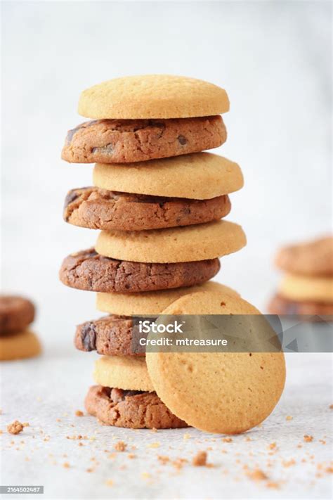 부스러기로 둘러싸인 갓 구운 교대 수제 쇼트 케이크 비스킷과 초콜릿 칩 쿠키의 스택에 기대어 있는 쇼트 브레드 라운드의 클로즈업 이미지 얼룩덜룩 한 흰색 배경 전경에 초점을