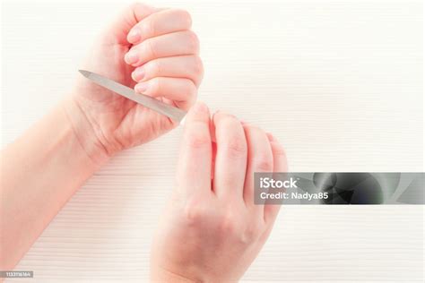 손톱 관리 절차를 받고 건강 한 자연 손톱 흰 여자의 손 하얀 여성 손 손톱 파일 흰색 나무 배경에 고립 손톱을 연마 뷰티 매니큐어 개인 위생 손톱 줄에 대한 스톡 사진 및