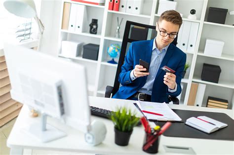 젊은 남자가 사무실에 테이블에 앉아서 은행 카드와 전화 개념에 대한 스톡 사진 및 기타 이미지 개념 경영자 경제학자