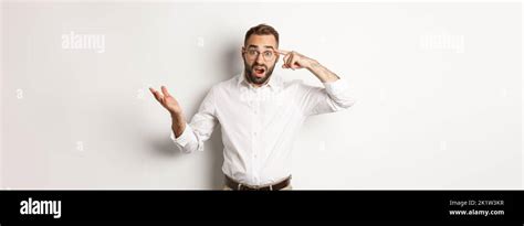 Confused And Shocked Man Pointing At Head Scolding Employee For Acting Stupid Standing Over