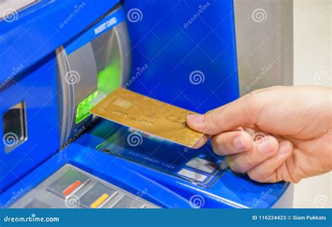 Closeup Woman Hand Inserting Debit Card Into An Atm Machine Stock