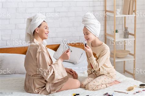 사랑스러운 여자와 그녀의 딸은 집에서 침대에 립스틱을 적용 메이크업과 재미를 홈웨어와 목욕 수건에 2명에 대한 스톡 사진 및 기타 이미지 Istock